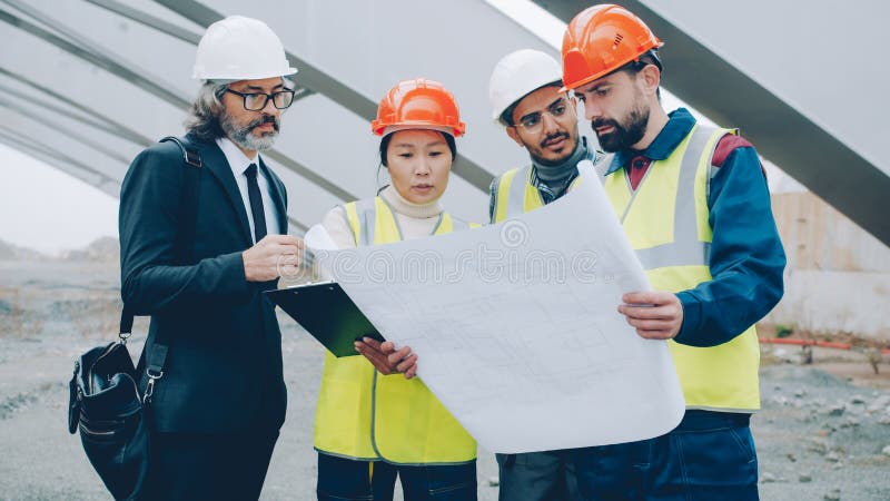 Construction Workers Discussing Project with Manager Standing in ...