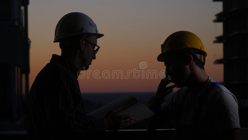 Construction Workers Having Discussion at Sunset. One Smokes Stock ...