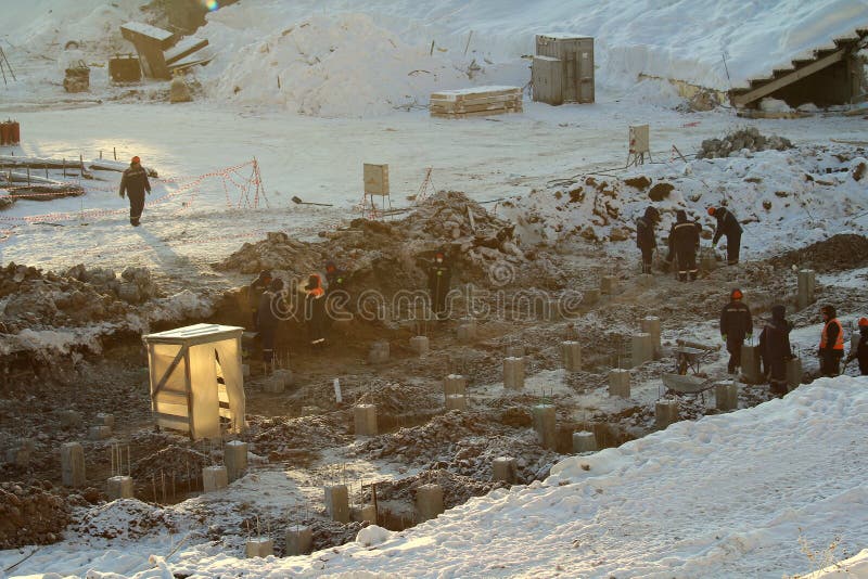Construction Workers in Overalls in Orange Helmets Work at a ...