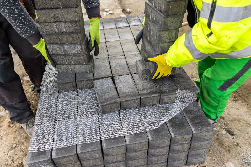 Construction Workers Placing Paving Stones on Mesh for Road Paving ...
