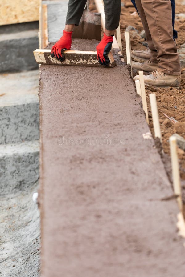 Construction Workers Pouring and Leveling Wet Cement into Wood Framing ...