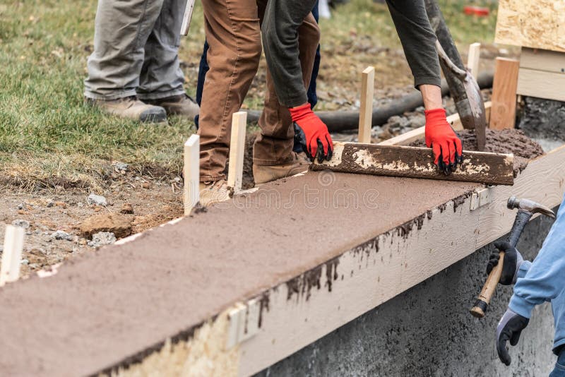 Construction Workers Pouring and Leveling Wet Cement into Wood Framing ...