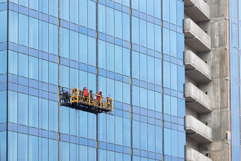 Construction Workers on a Suspended Cradle Mount the Glass Facade of a ...