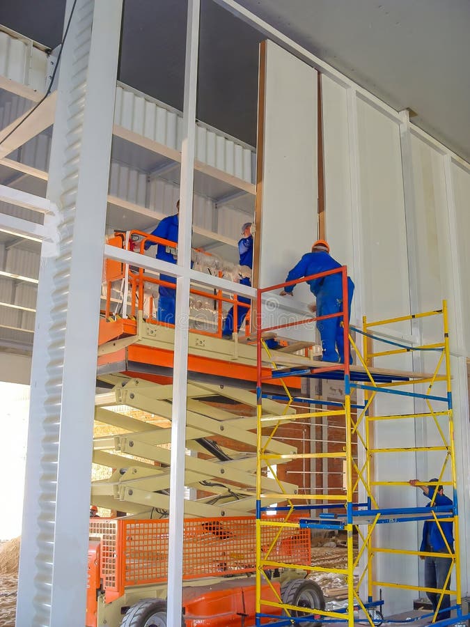 Construction Workers Use a Scissor Lift and Scaffolding To Install ...