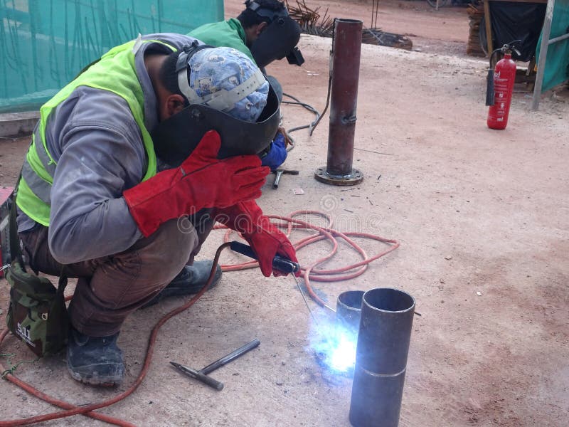 Construction Workers Welding Pipes at the Construction Site. Editorial ...