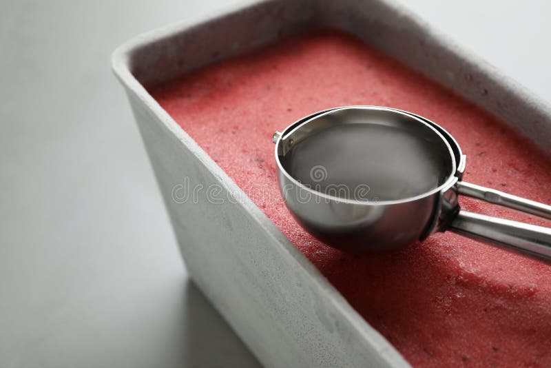 Container with Delicious Pink Ice Cream and Scoop on Grey Table Stock ...