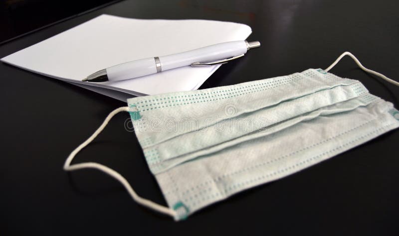 Containment Surgical Face Mask Next To Paper Notepad and Pen on a Desck ...
