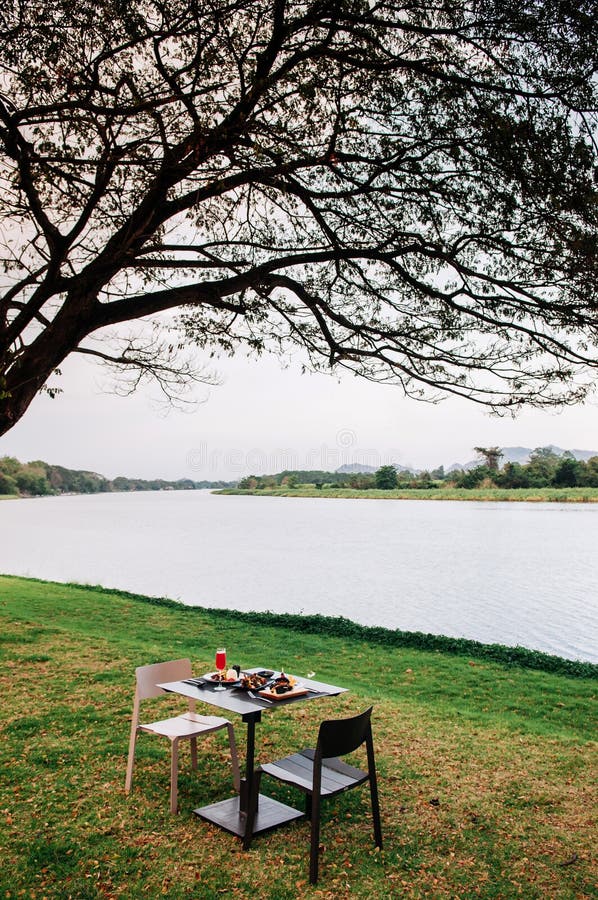 Contemporary Dinner Table Under Big Tree in Park by the River Stock ...