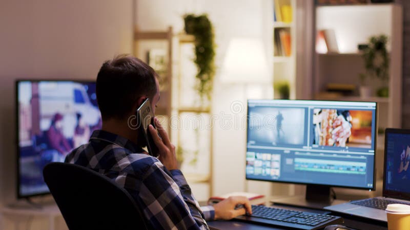 Content Creator Talking on the Phone while Working on a Multimedia ...