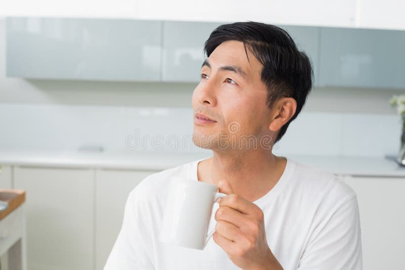 Content Man Drinking Coffee As he Looks Away in Kitchen Stock Image ...