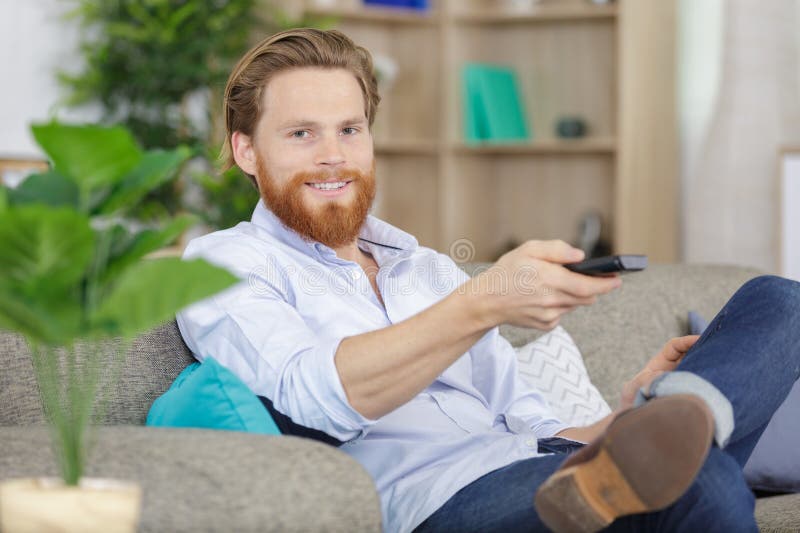 Contented Man on Sofa Using Tv Remote Control Stock Photo - Image of ...