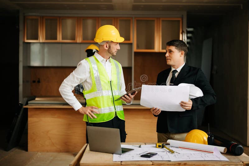 Contractor and Architect Looking at Plan, Tablet, Laptop and Talking ...