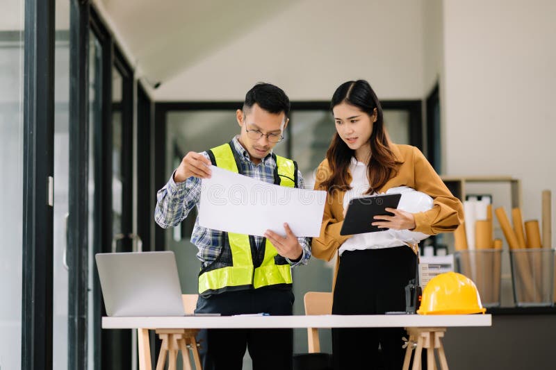 Contractor and Architect Looking at Plan, Tablet, Laptop and Talking ...