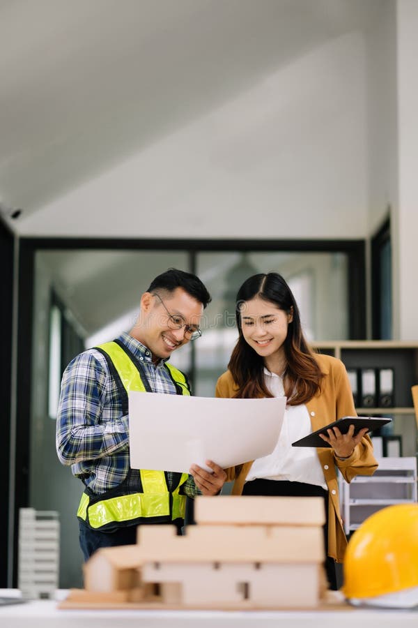 Contractor and Architect Looking at Plan, Tablet, Laptop and Talking ...