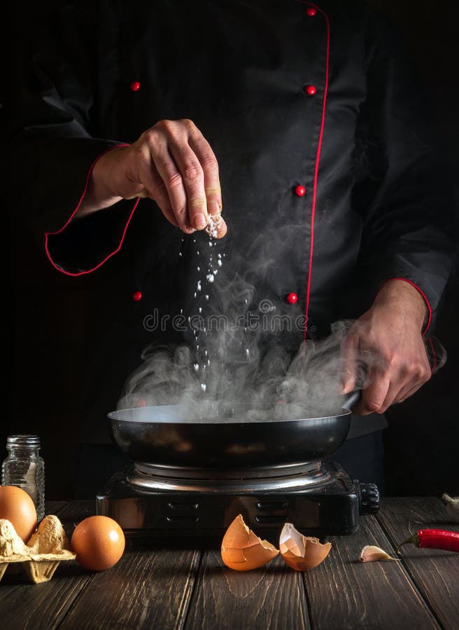 The Cook Adds Salt while Cooking Eggs in Pan. Work Environment on ...