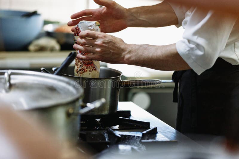 Cook Cooks in a Restaurant Kitchen, Sprinkles Spices into the Pan Stock ...