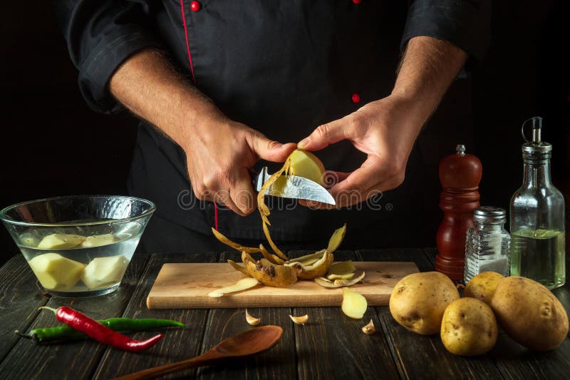 The Cook Cuts Raw Potatoes into Pieces with a Knife before Preparing ...