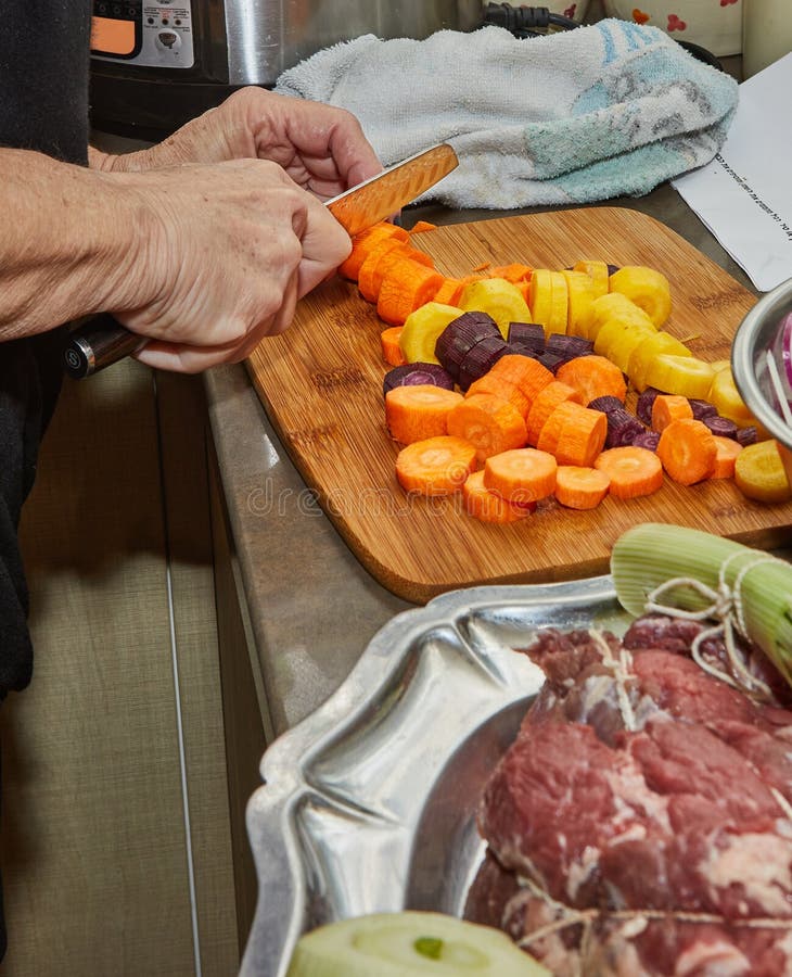 Cook Cuts Three-color Carrots into Slices on Wooden Board in the ...