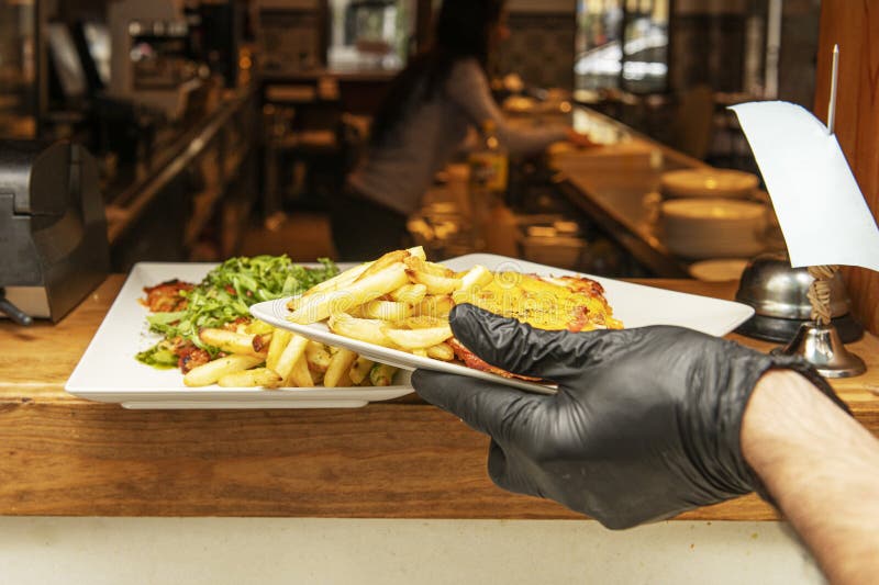 A Cook Passing the Finished Order through the Serving Hatch in the ...