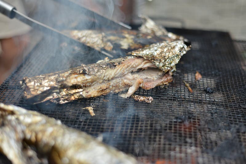 The Cook Prepares Baked Fish in Foil Over the Fire Stock Image - Image ...