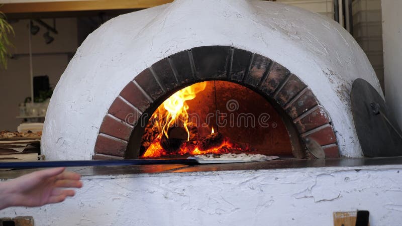 The Cook Puts the Pizza To Bake in the Oven with Fire Using a Spatula ...