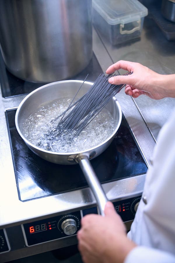 Cook Puts a Portion of Black Spaghetti into Boiling Water Stock Photo ...