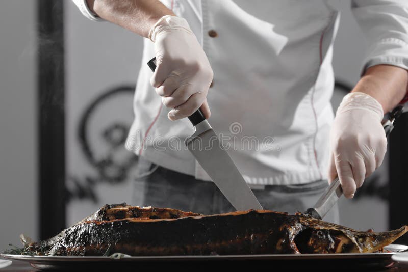 Cooked Fish in a Professional Kitchen. Chef Cuts Sturgeon Fish. Stock ...