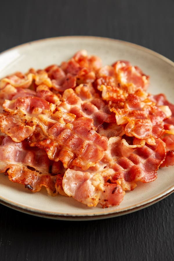 Cooked Greasy Bacon on a Plate on a Black Background, Side View Stock ...