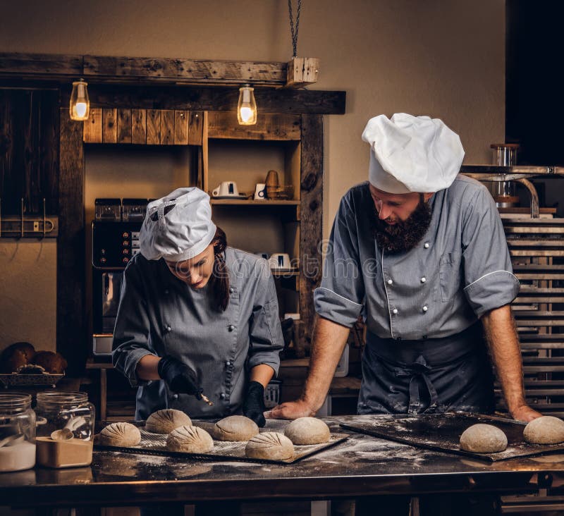Chef Teaching His Assistant To Bake the Bread in a Bakery. Stock Photo ...
