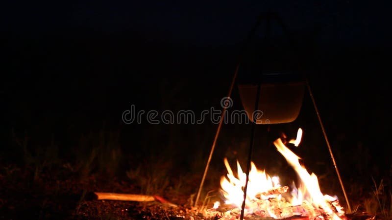 A Campfire at Night with a Pot Hanging Over it, in Which Food is Being ...