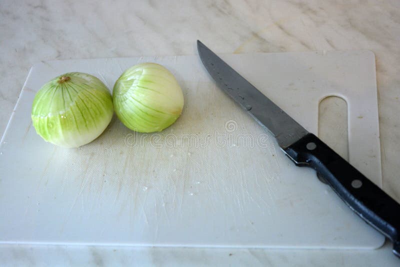 A Large White Green Onion and a Utility Knife with a Black Handle Lie ...