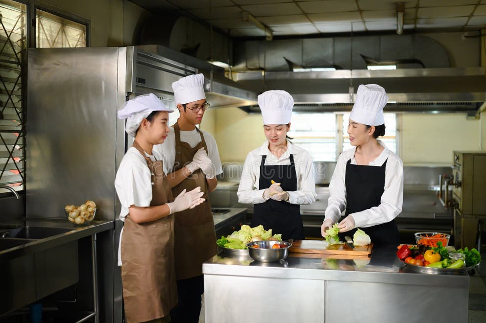 Cooking Teacher Demonstrating Vegetable Preparation Techniques To Group ...