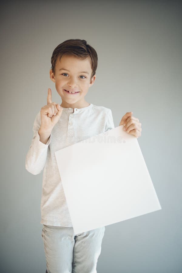 Cool Young Boy is Holding White Sign in Front of Grey Background during ...