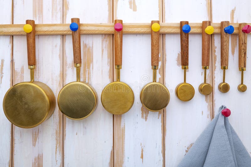 Copper Measuring Cups with Wooden Handles Hang on the Wall in the ...