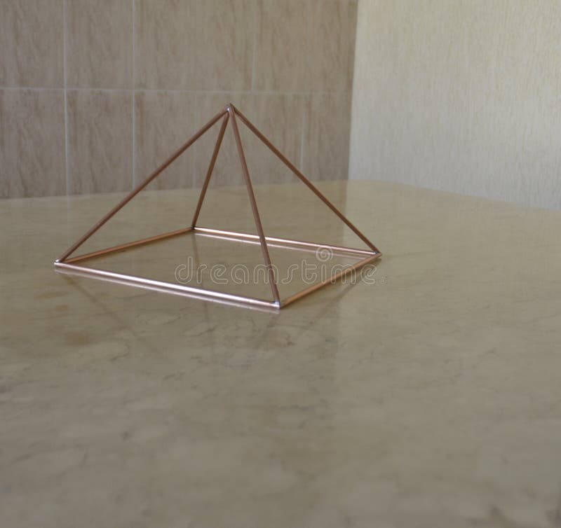 Copper Pyramid on a Travertine Marble Table and Ceramic Tile Background ...