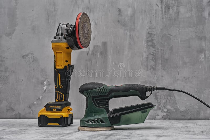 Cordless Grinder and a Sander Rest on a Concrete Surface Against a ...