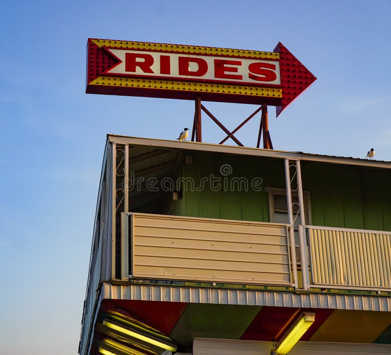 Corner of a Building with an Arrow Shaped Sign for Amusement Park Rides ...