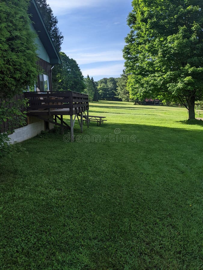 A Cottage with a Wooden Deck on a Grass Field Stock Image - Image of ...