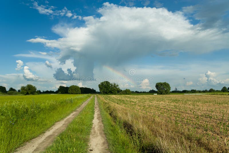 Country Road through Fields and a Small Rainbow on the Sky Stock Photo ...