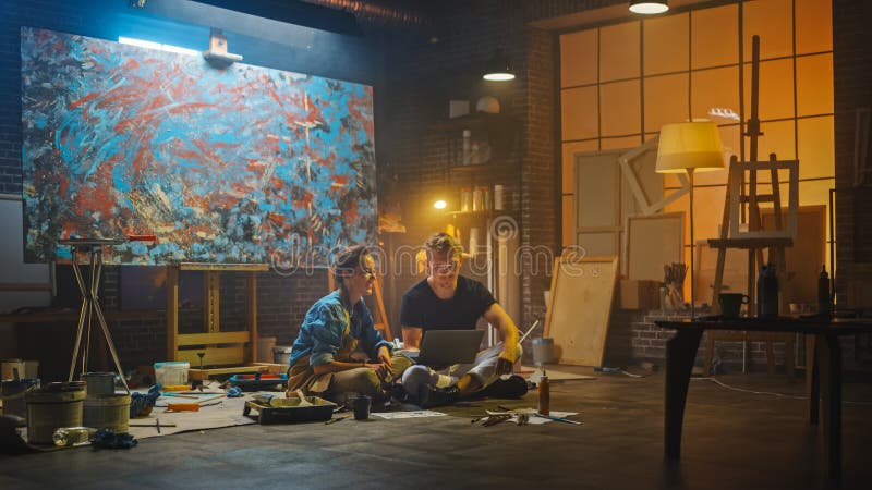 Couple of Artists Sitting in Their Studio Use Laptop Computer, Working ...