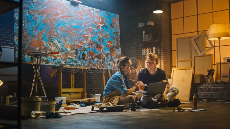 Couple of Artists Sitting in Their Studio Use Laptop Computer, Working ...