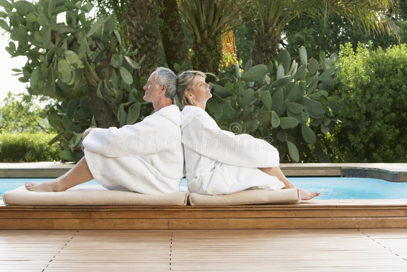 Couple in Bathrobes Sitting Back To Back by Pool Stock Image - Image of ...