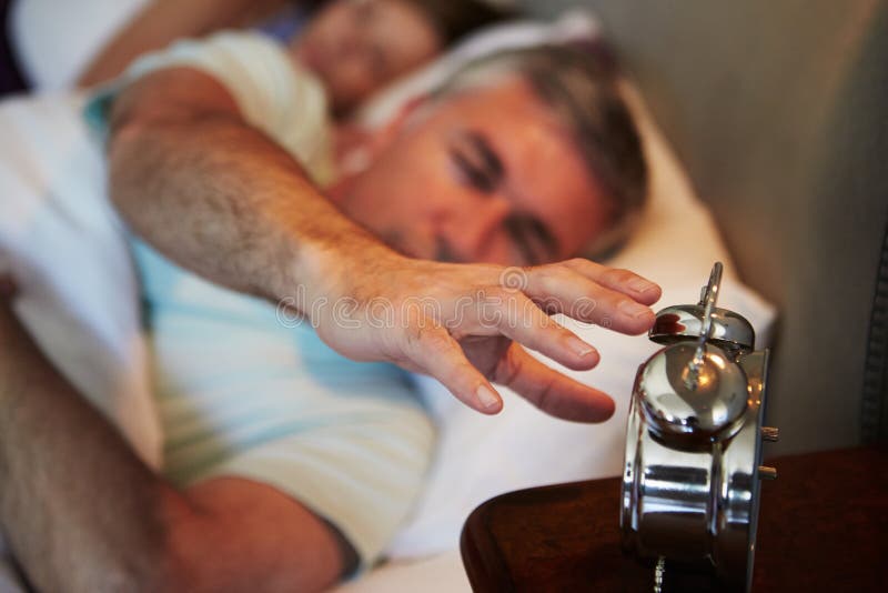 Couple in Bed with Man Reaching To Switch Off Alarm Clock Stock Image ...