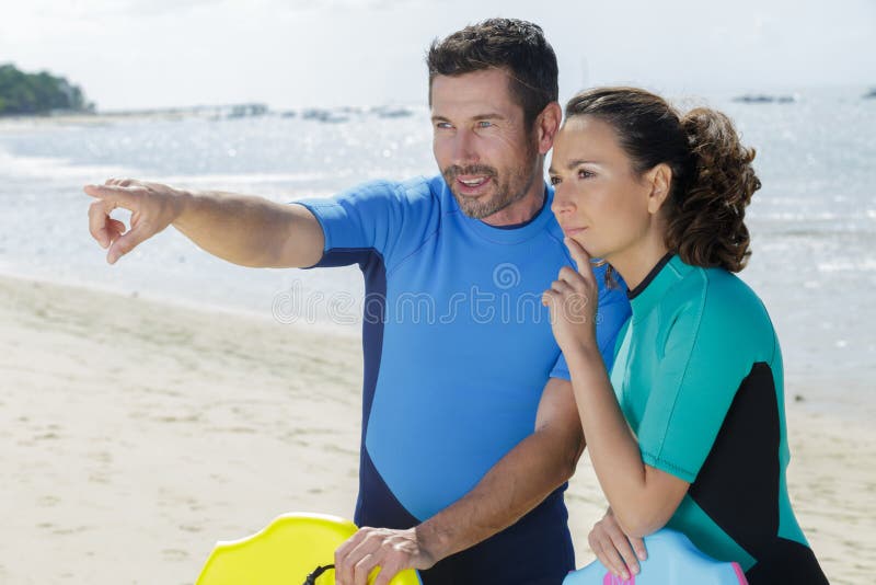 Couple with Boogie Boards Looking and Pointing Up Beach Stock Image ...