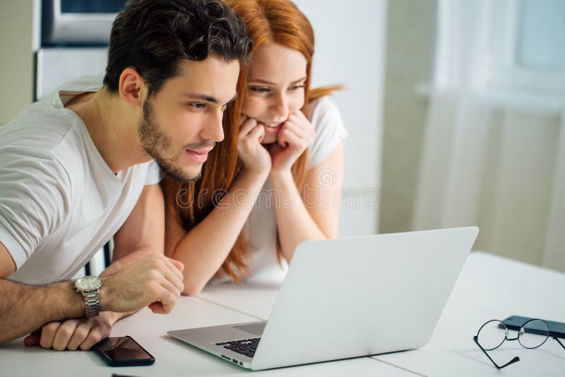Couple Browsing Internet Together Sitting at Table and Smiling and Read ...