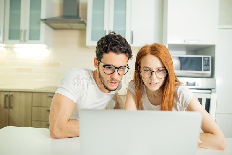 Couple Browsing Internet Together Sitting at Table and Smiling and Read ...