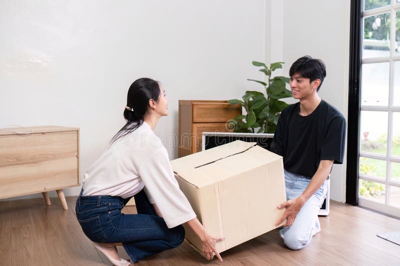 Dedicated Couple Working Together To Lift a Moving Box in Their New ...