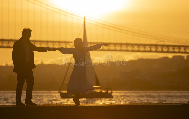 Couple Dancing by the River at Sunset with Bridge in Background Stock ...