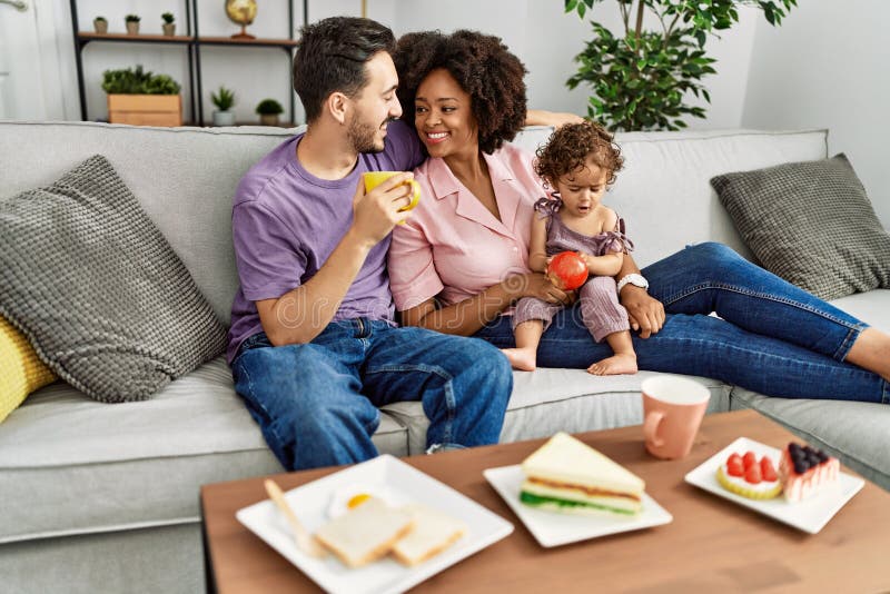 Couple and Daughter Having Breakfast Sitting on Sofa at Home Stock ...