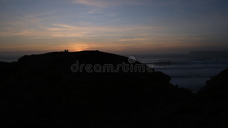 A Couple in the Distance at Sunset Over the Atlantic Stock Photo ...